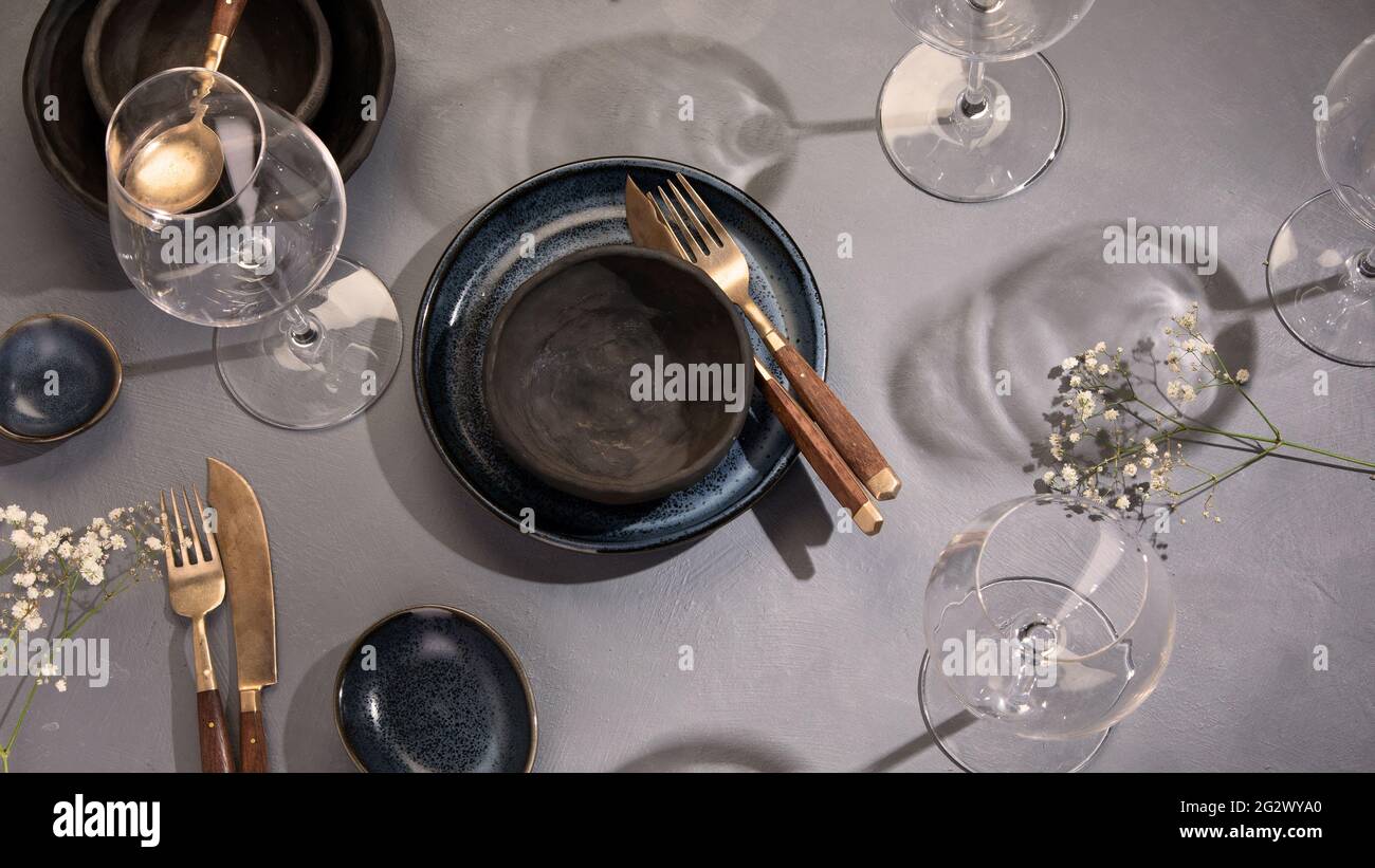 Table setting with a black and blue plates on gray background ...