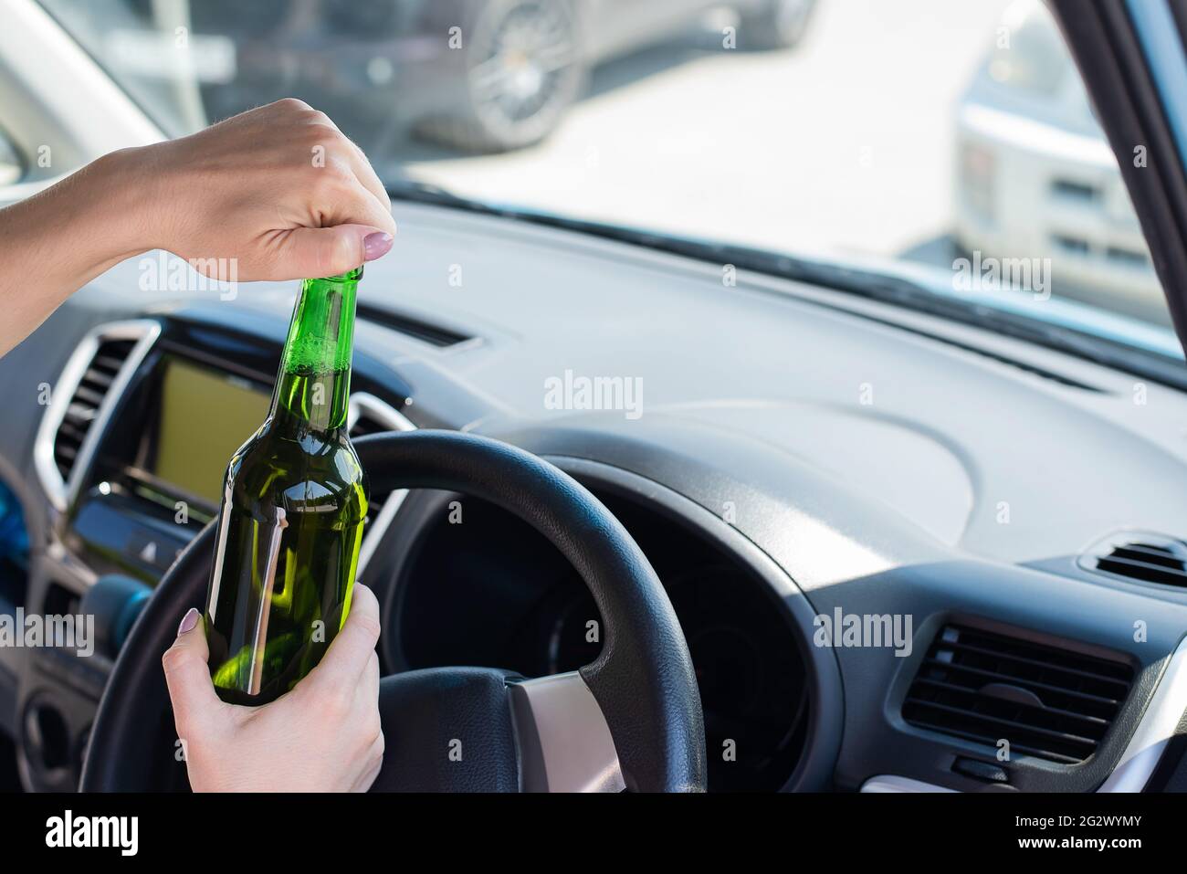 A faceless woman opens a bottle of beer while driving a car. Breaking ...