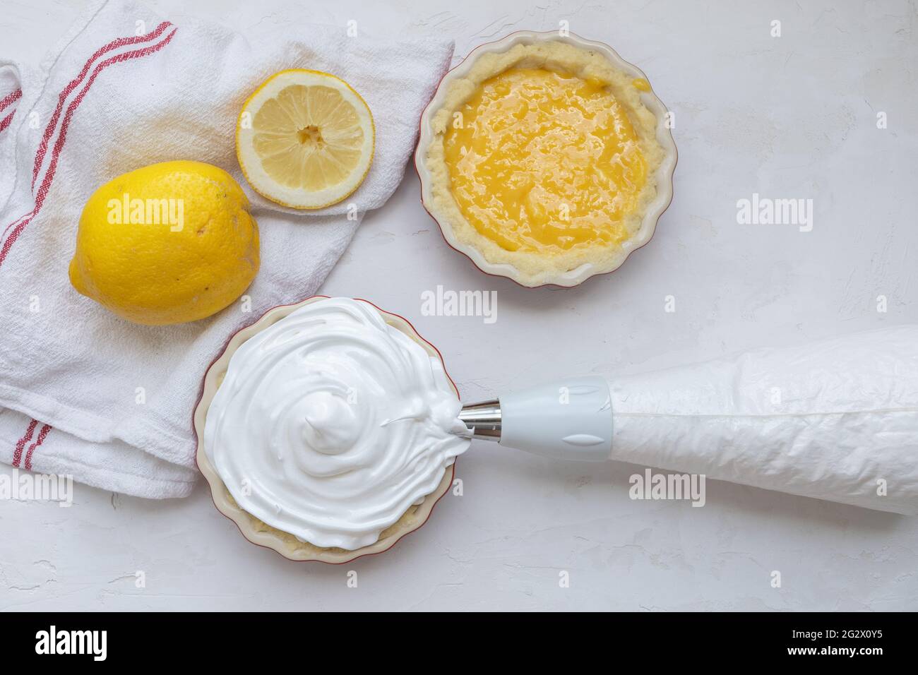 Making of mini lemon meringue pies in tartlet forms, one with, one ...
