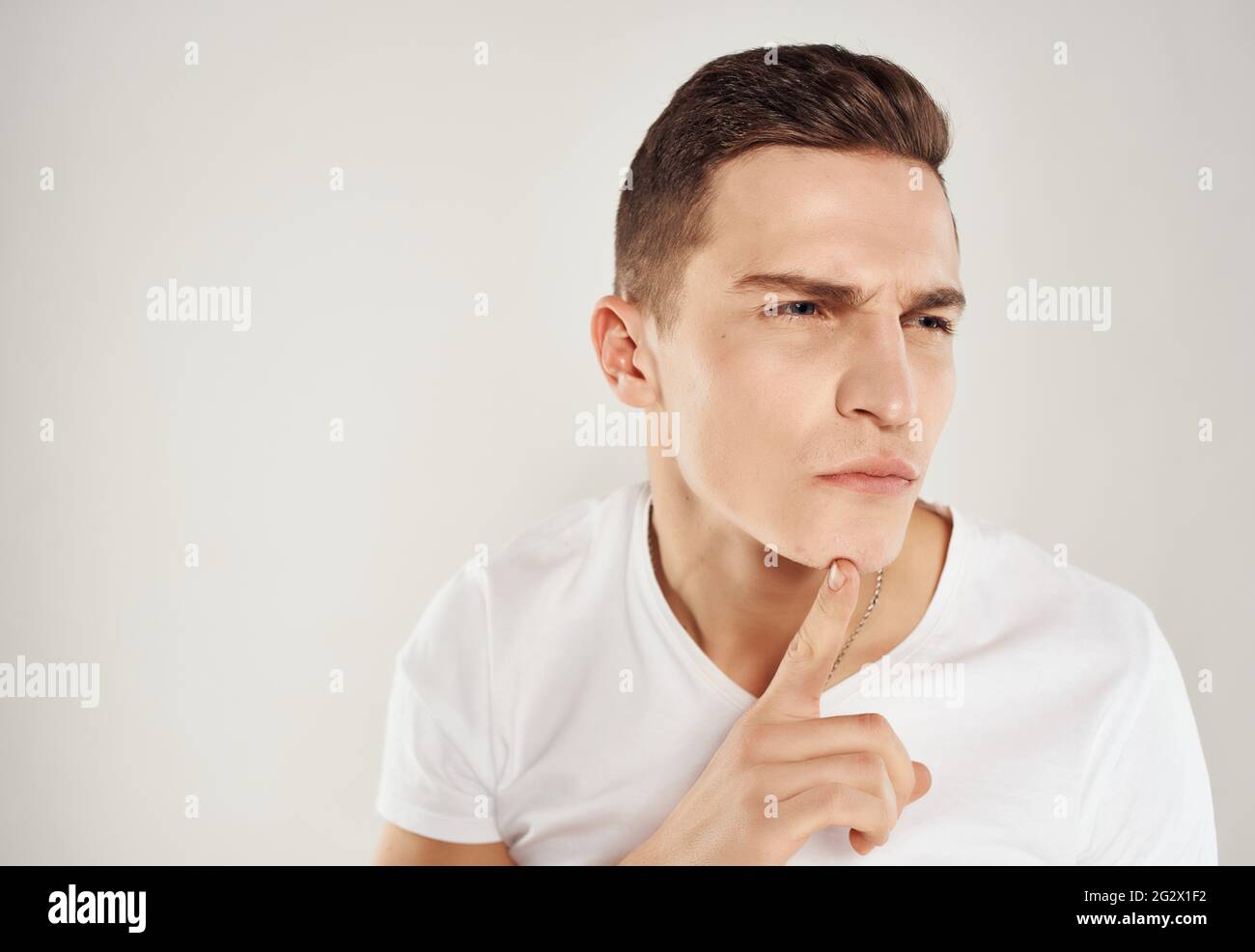 a man with a serious expression that in a white t-shirt suspicious look ...