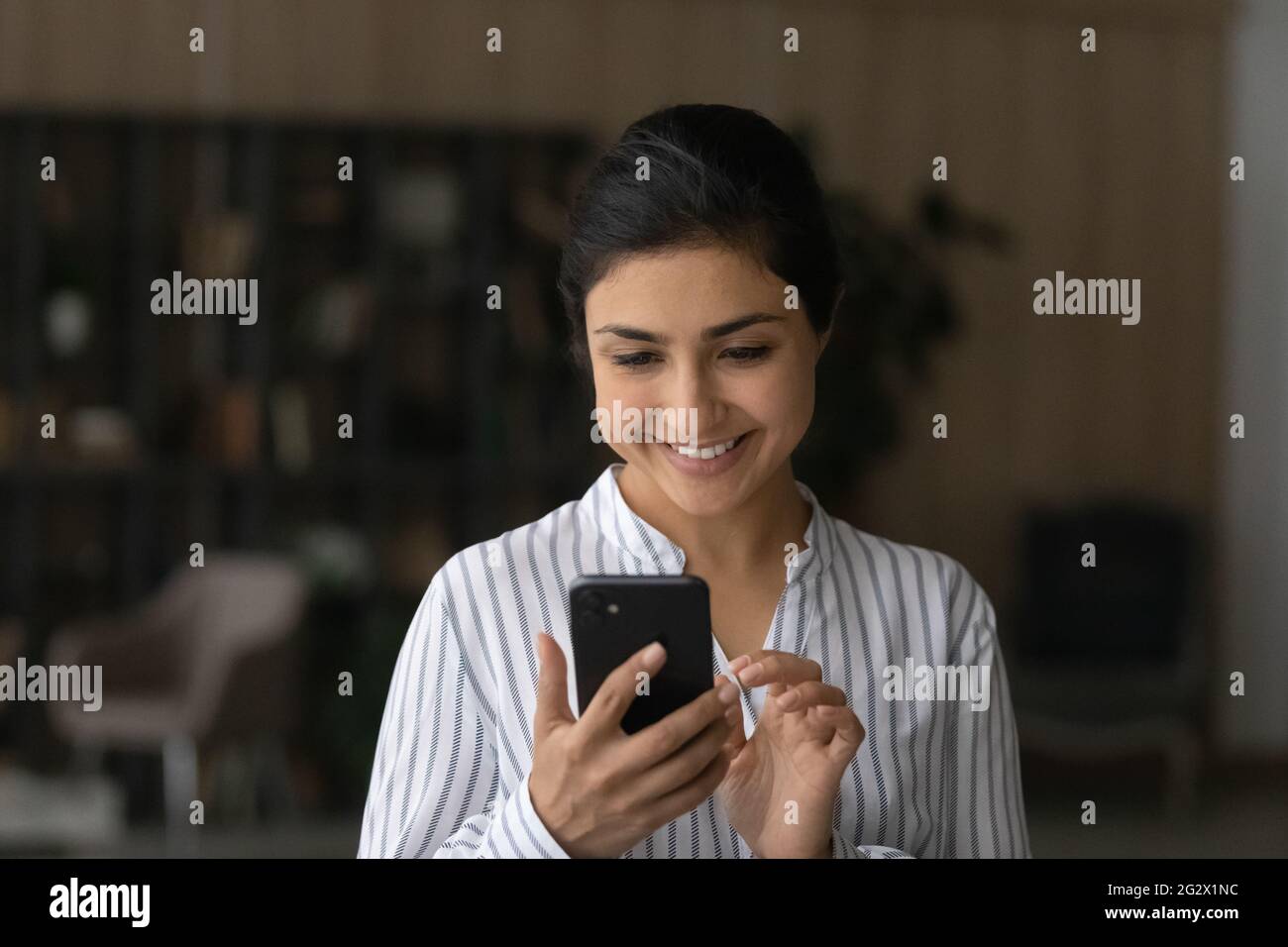 Happy young indian woman smartphone user chatting at social network ...
