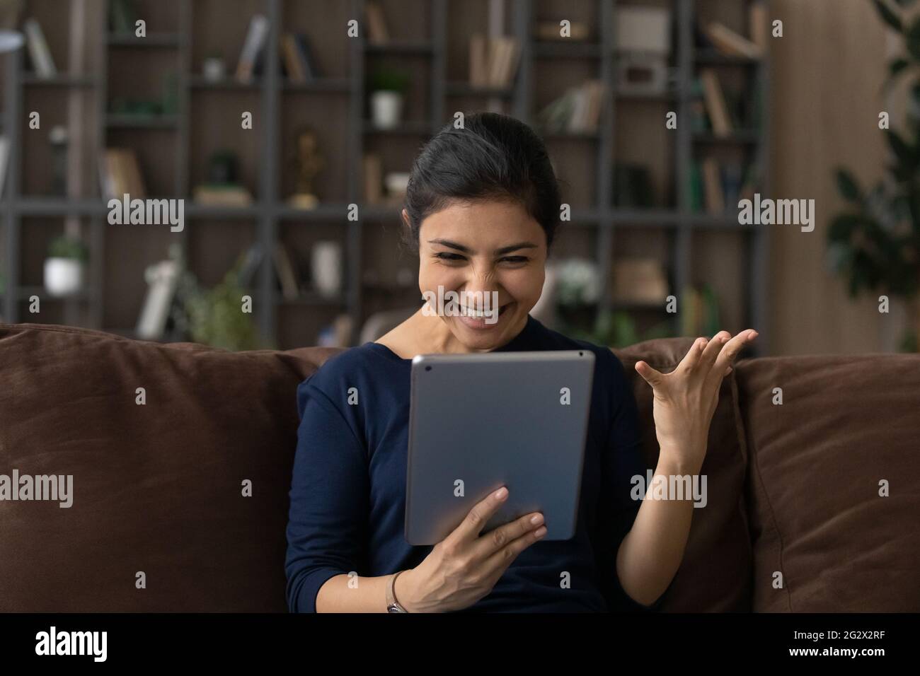 Emotional young indian lady splash hand look on tablet screen Stock ...