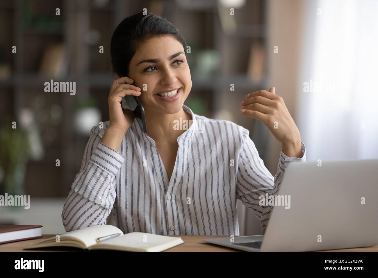 Indian woman employee make call from workplace distracted from pc Stock ...
