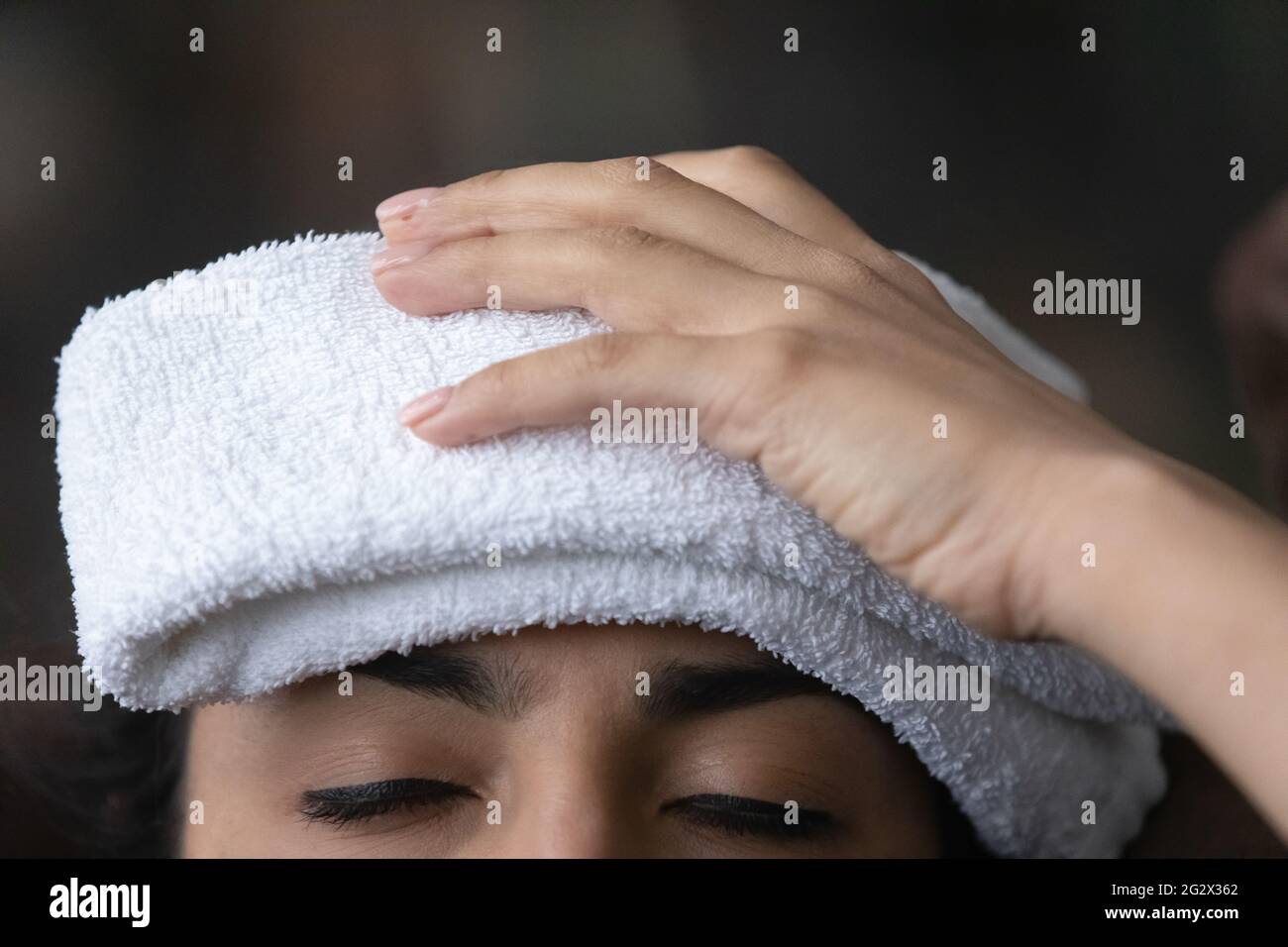 Sick young female having fever holding wet towel on head Stock Photo ...