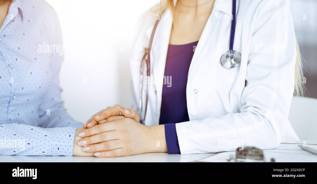 Unknown woman-doctor is holding her patient's hands to reassure a ...