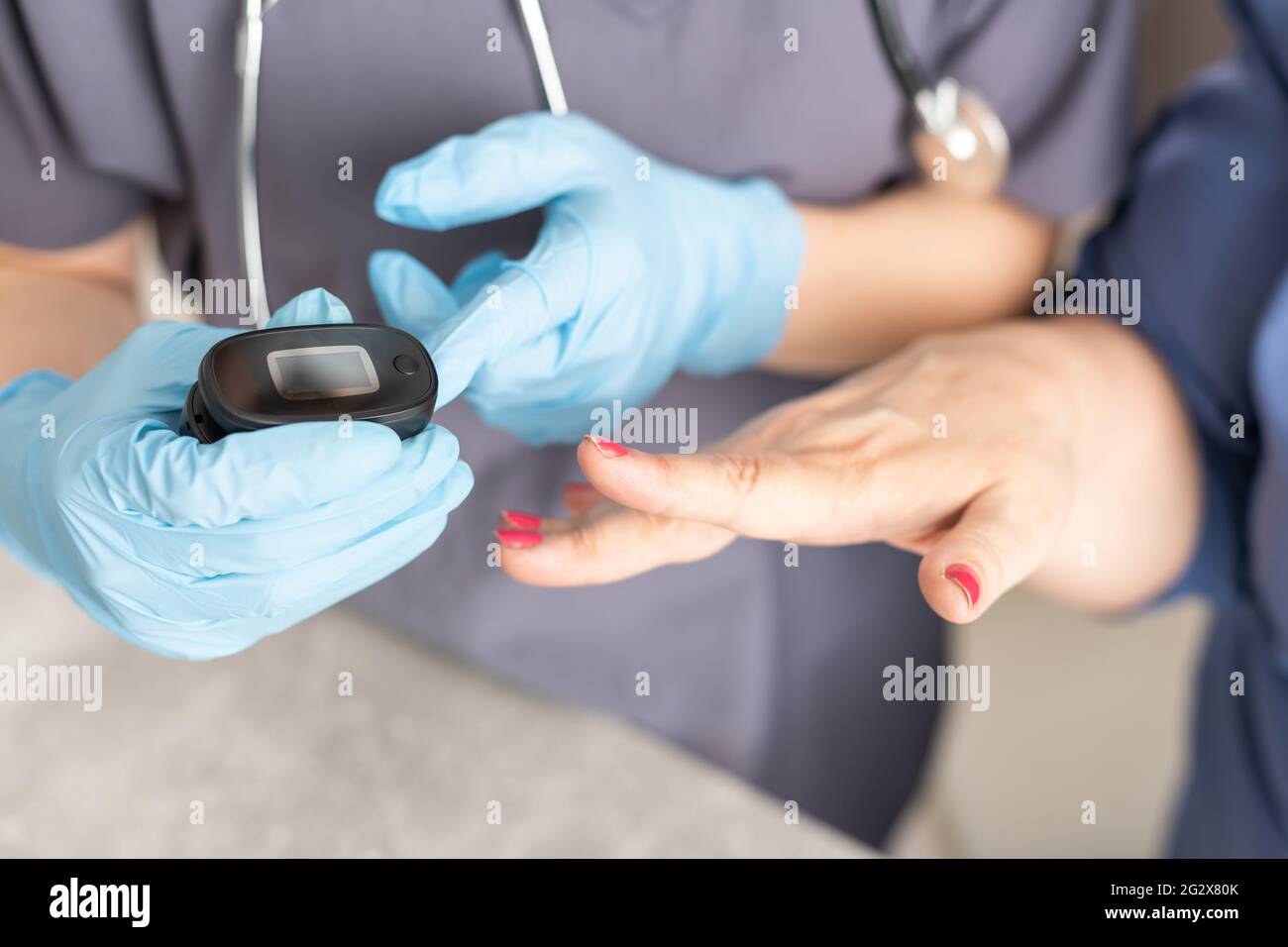 Nurse uses pulse oximeter to measure elderly patient's blood oxygen ...