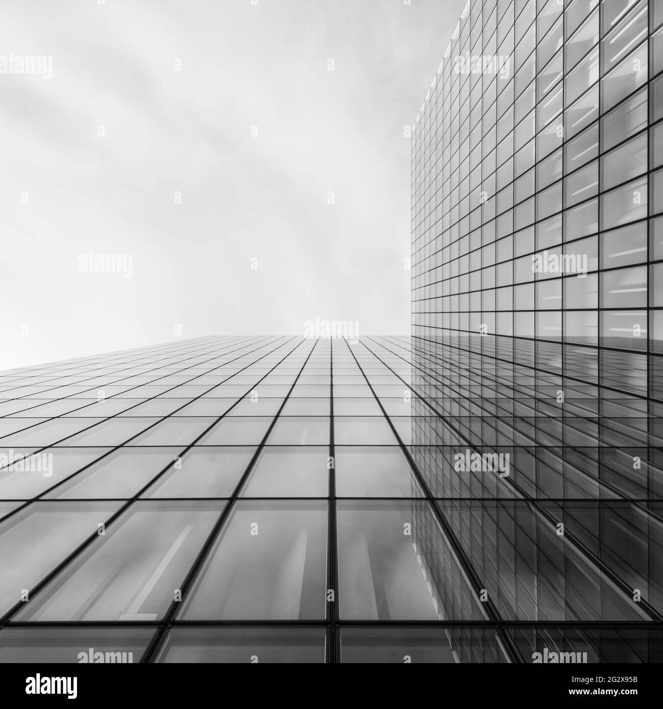 A vertical grayscale shot of a modern building with glass walls Stock ...