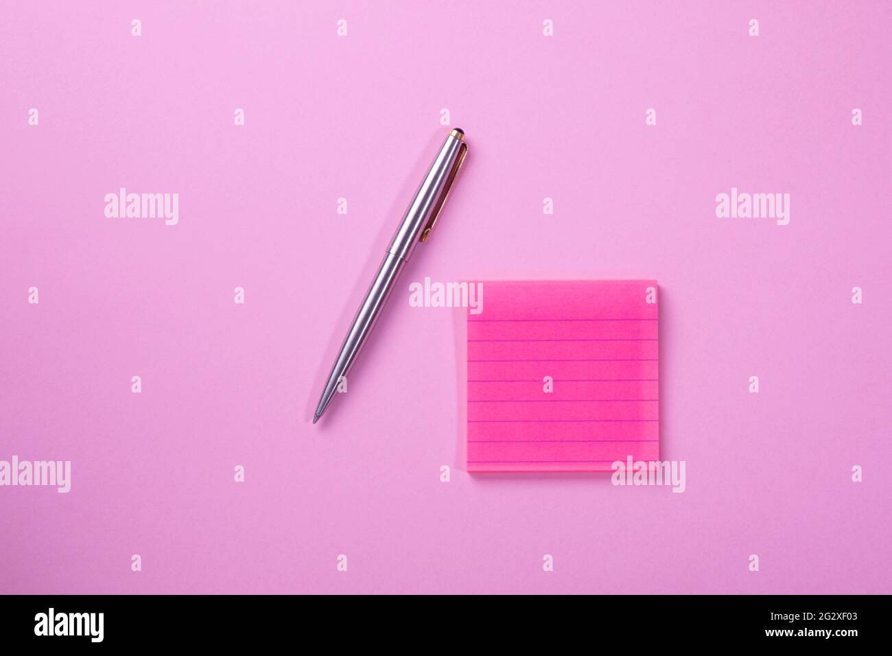 Neon pink square sticky notepad with silver ballpoint pen on pink ...