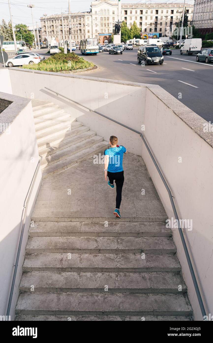 Young man running upstairs on city stairs. Fitness, sport, people ...