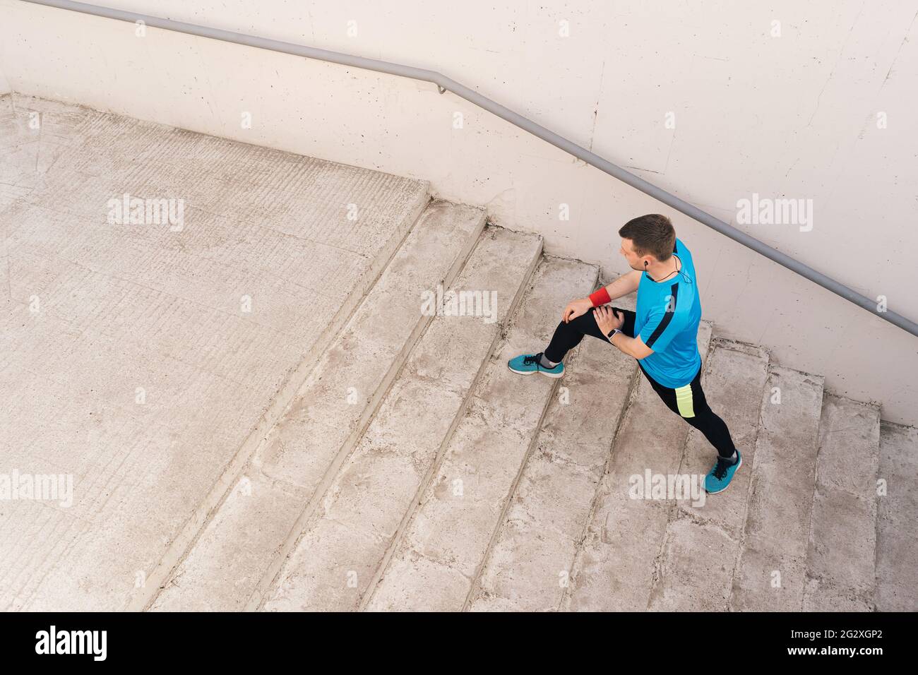 Young man runner getting ready to run stretching legs warm up quad ...