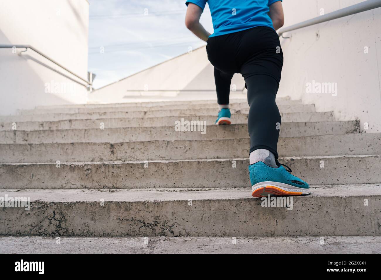 Young man runner getting ready to run stretching legs warm up quad ...
