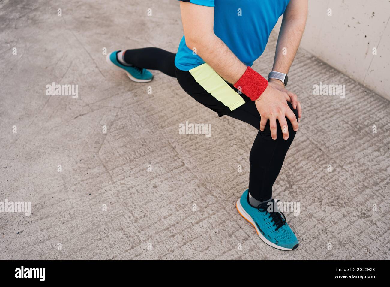 Young man runner getting ready to run stretching legs warm up quad ...