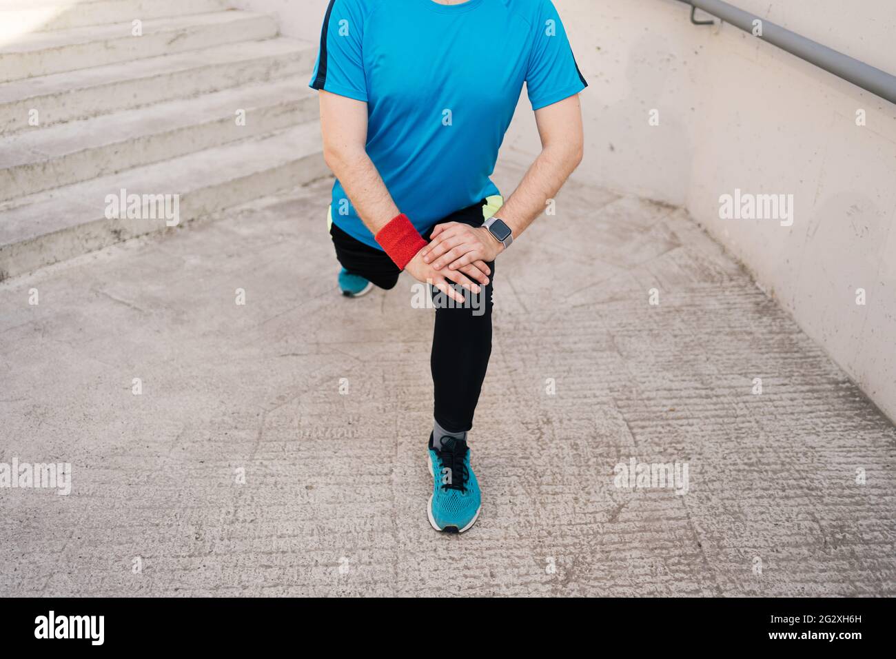 Young man runner getting ready to run stretching legs warm up quad ...