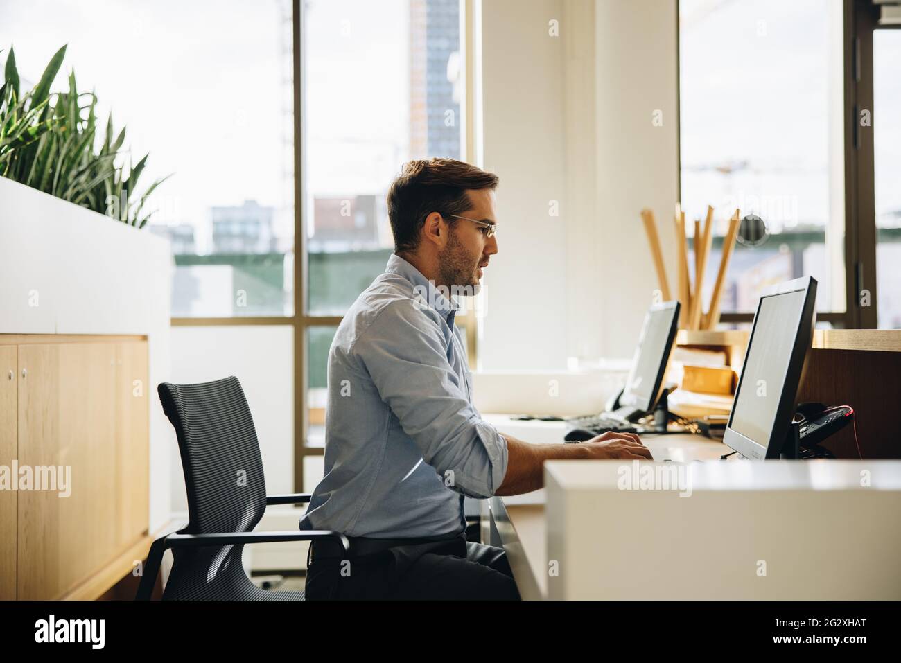 Side view of young executive working on computer in office. businessman ...