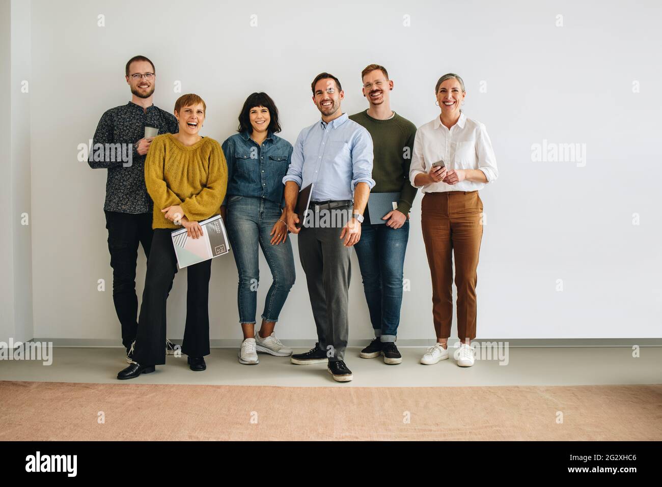 Business team standing at wall and smiling at camera. Group of office ...