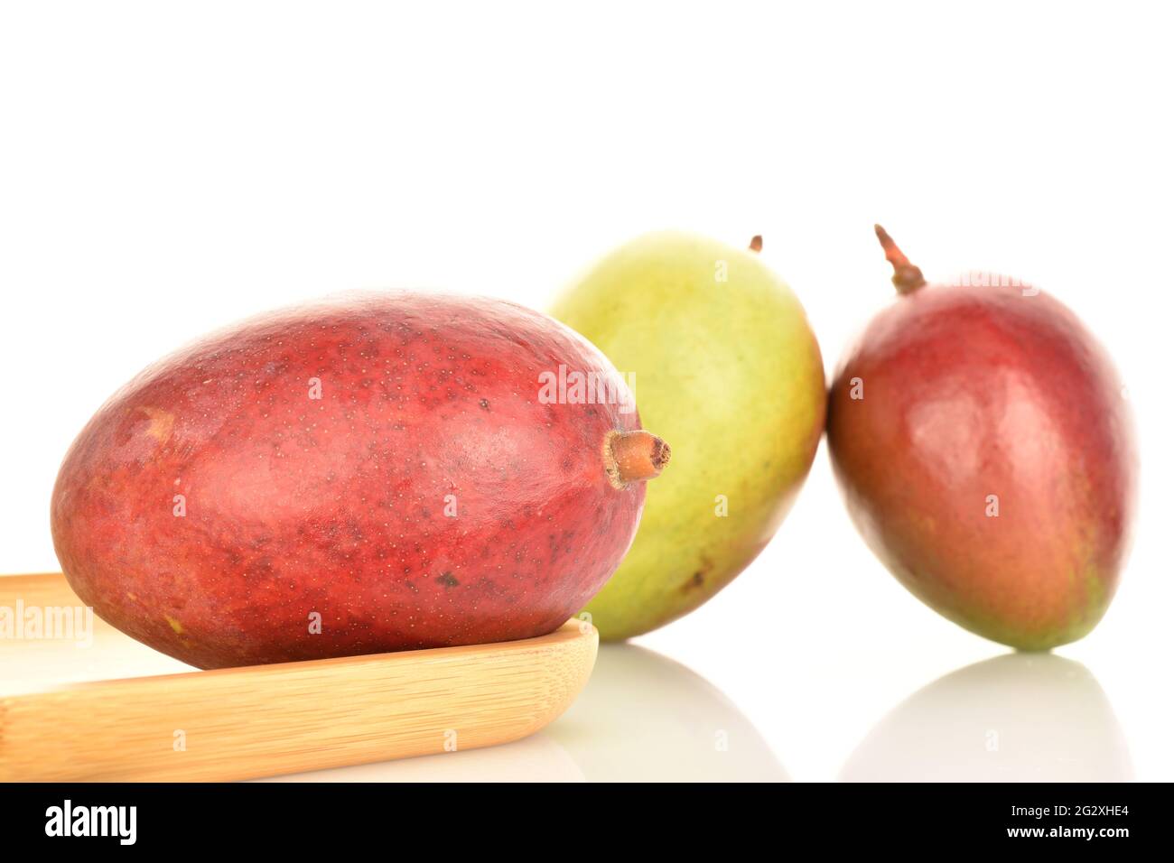 Three ripe mangoes with a bamboo plate, close-up, on a white background ...