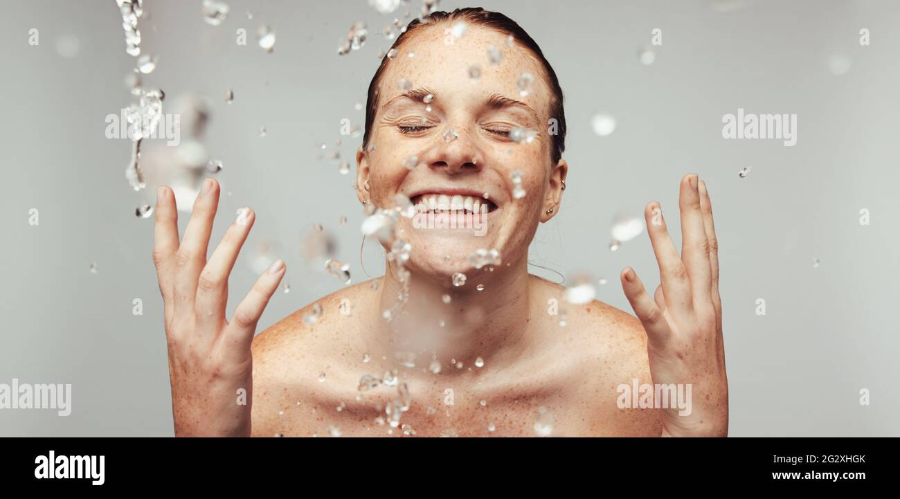 Close up of young woman with freckles on skin. Happy woman splashing ...