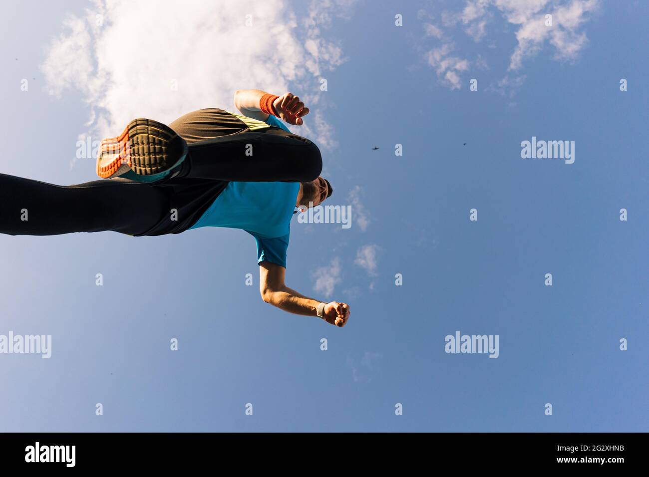 Low angle view of a sportsman who jump and run with blue sky in ...
