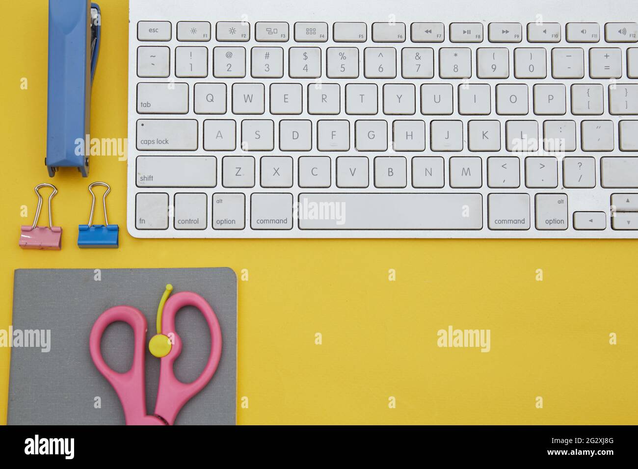 A top view of a paper stapler, paper clips, scissors, and a keyboard on ...