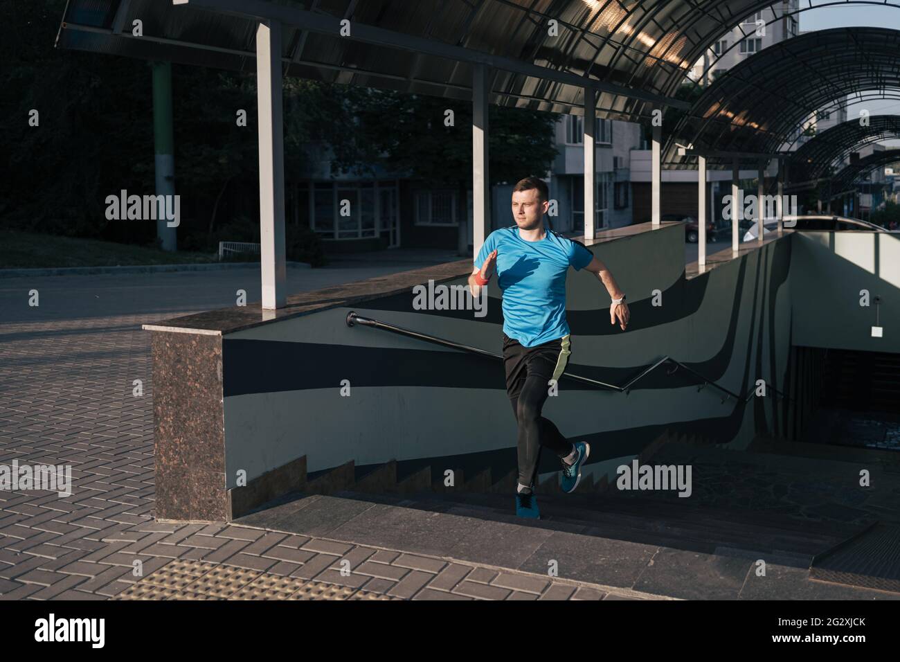 Young man running upstairs on city stairs. Fitness, sport, people ...