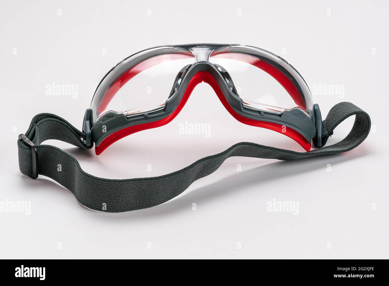Red frame working goggles with black elastic strap on white background ...