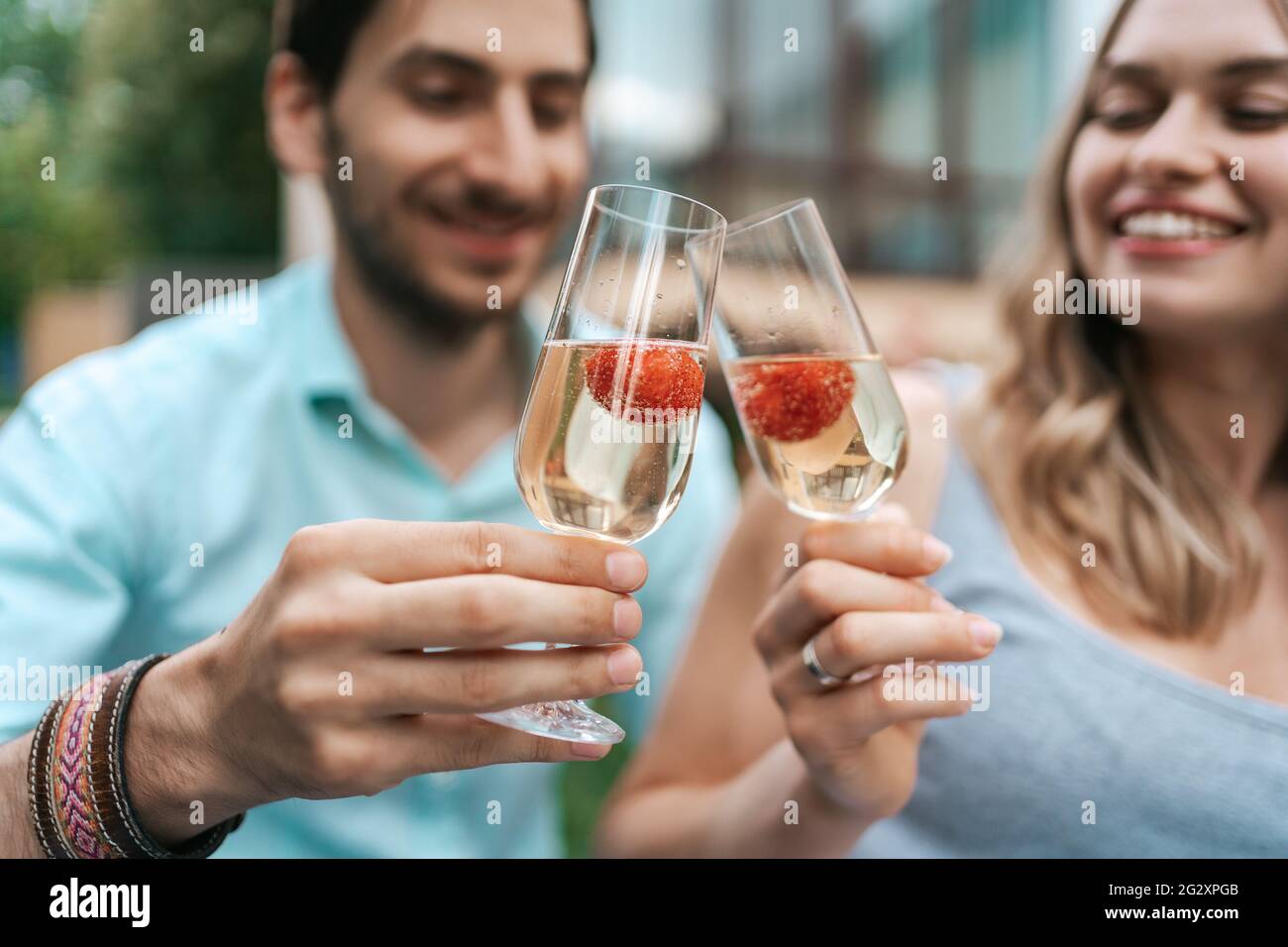 Happy couple portrait clinking two glasses with sparkling wine and strawberries inside with ...