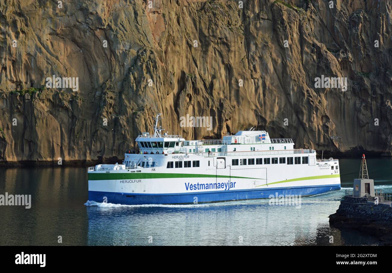The Icelandic ferry Herjolfur sailing close to a sheer rock cliff face ...