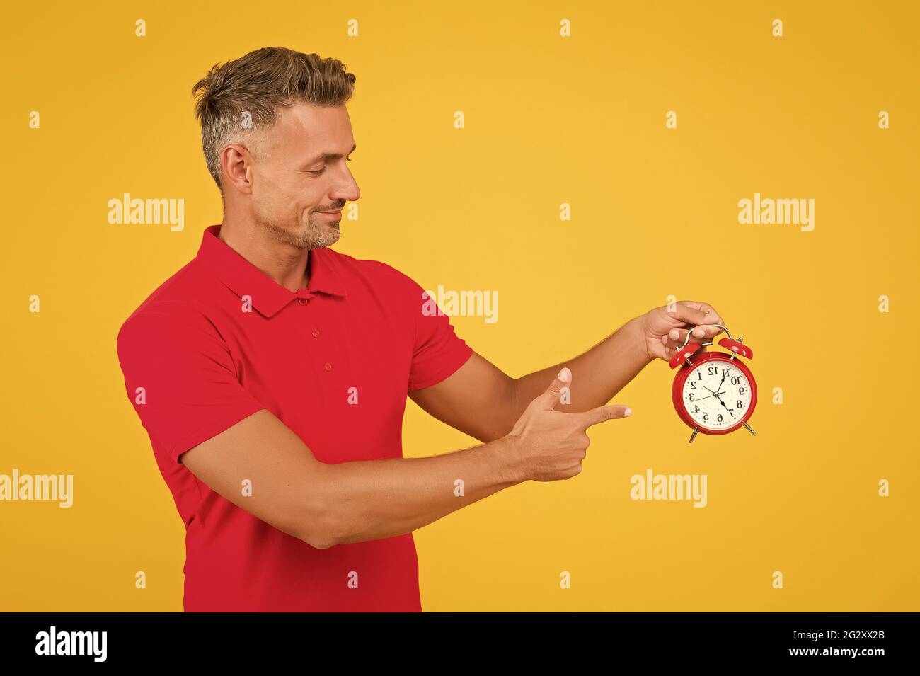 Look at clock. Handsome man point finger at alarm clock. Check current ...