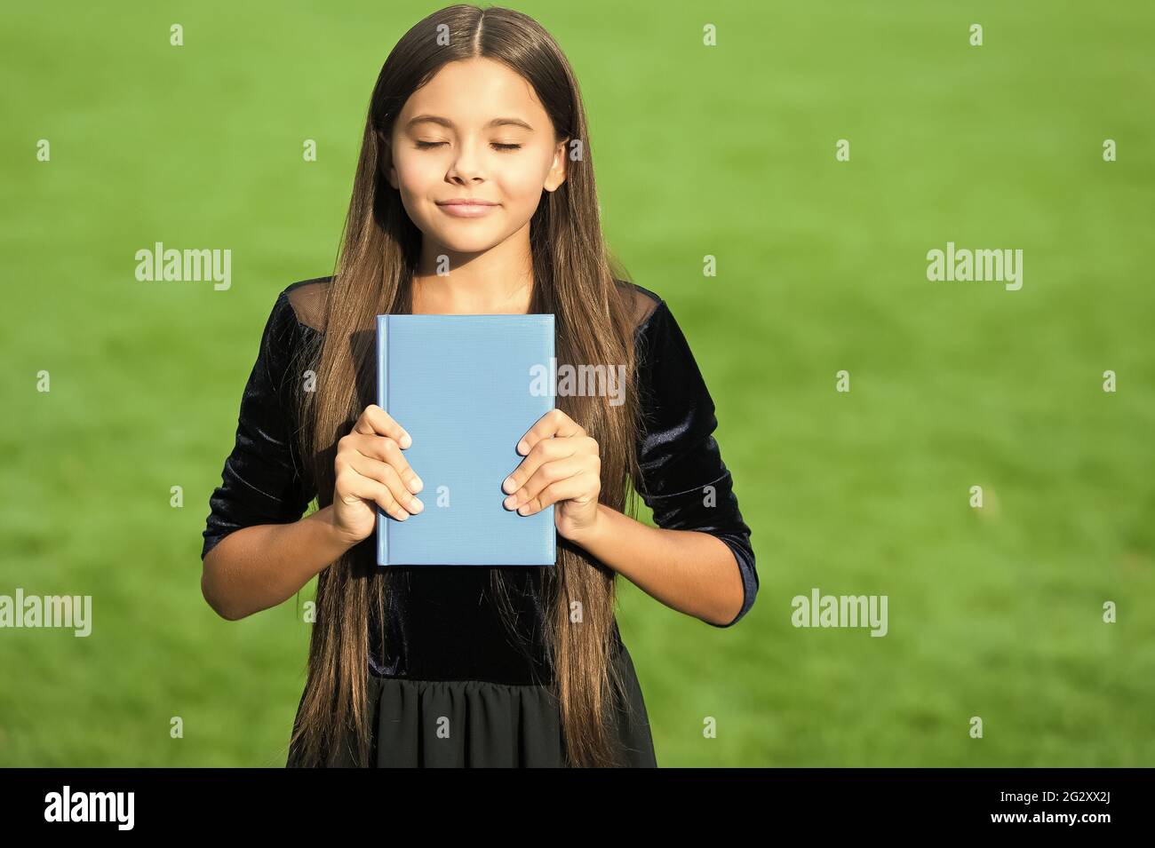 Learning by heart. Happy child learn from book with closed eyes. School ...