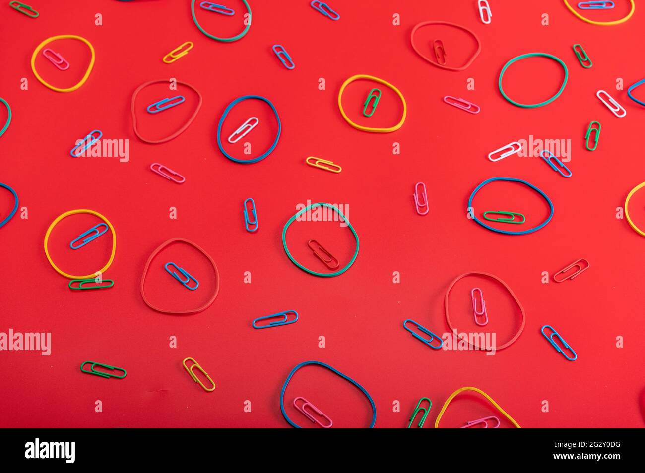 Stationery rubber bands and paper clips on a red background. Red ...