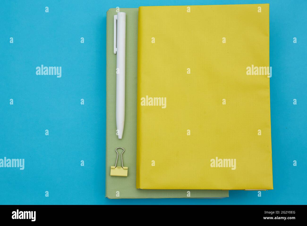 A top view of a notebook, a pen, and a paper clip on a blue background ...