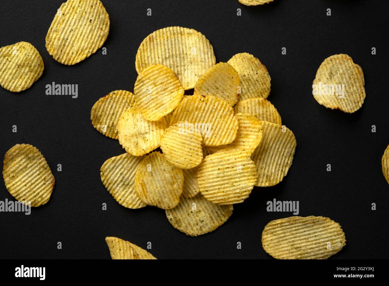 Pile of ridged potato chips black background, top view Stock Photo - Alamy