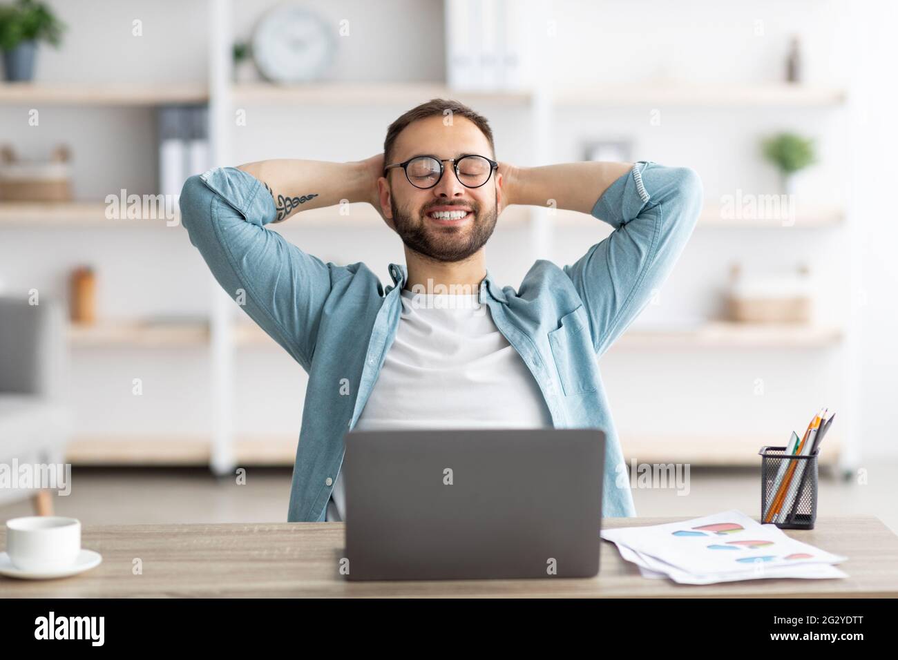Smiling Caucasian businessman having rest in front of laptop computer ...