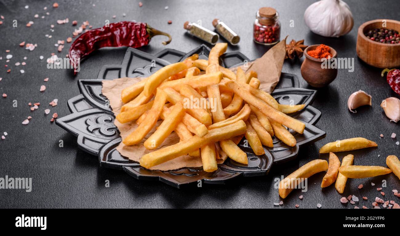Tasty fried french fries with salt and spices on a dark background ...