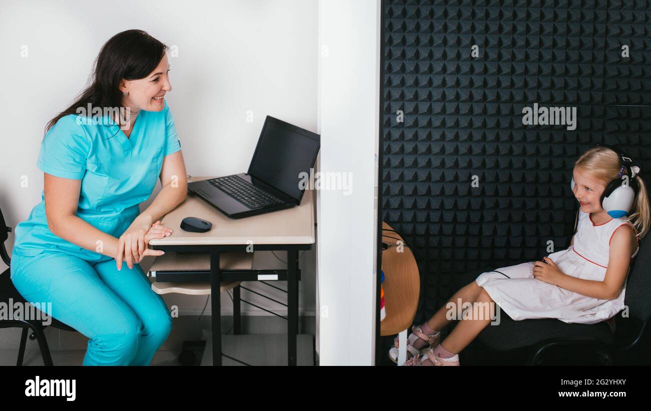 Audiologist doing a hearing test for a little girl. Child sitting at ...