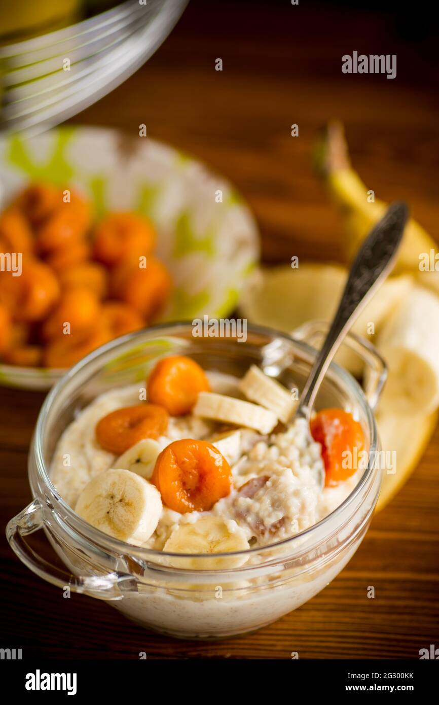 cooked boiled sweet oatmeal with with dried apricots and bananas in a ...