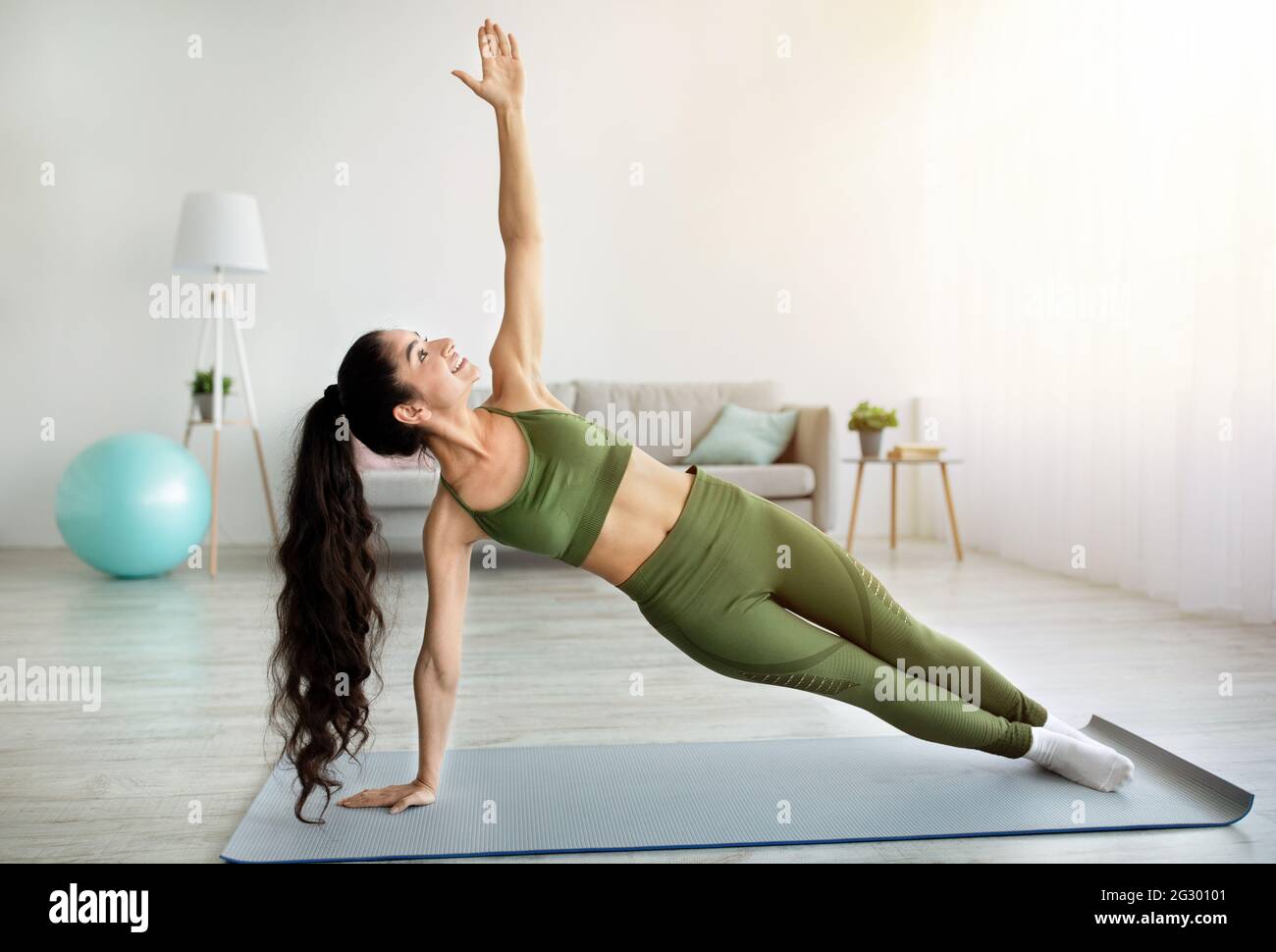 Fit Indian woman doing side plank on sports mat indoors, full length ...
