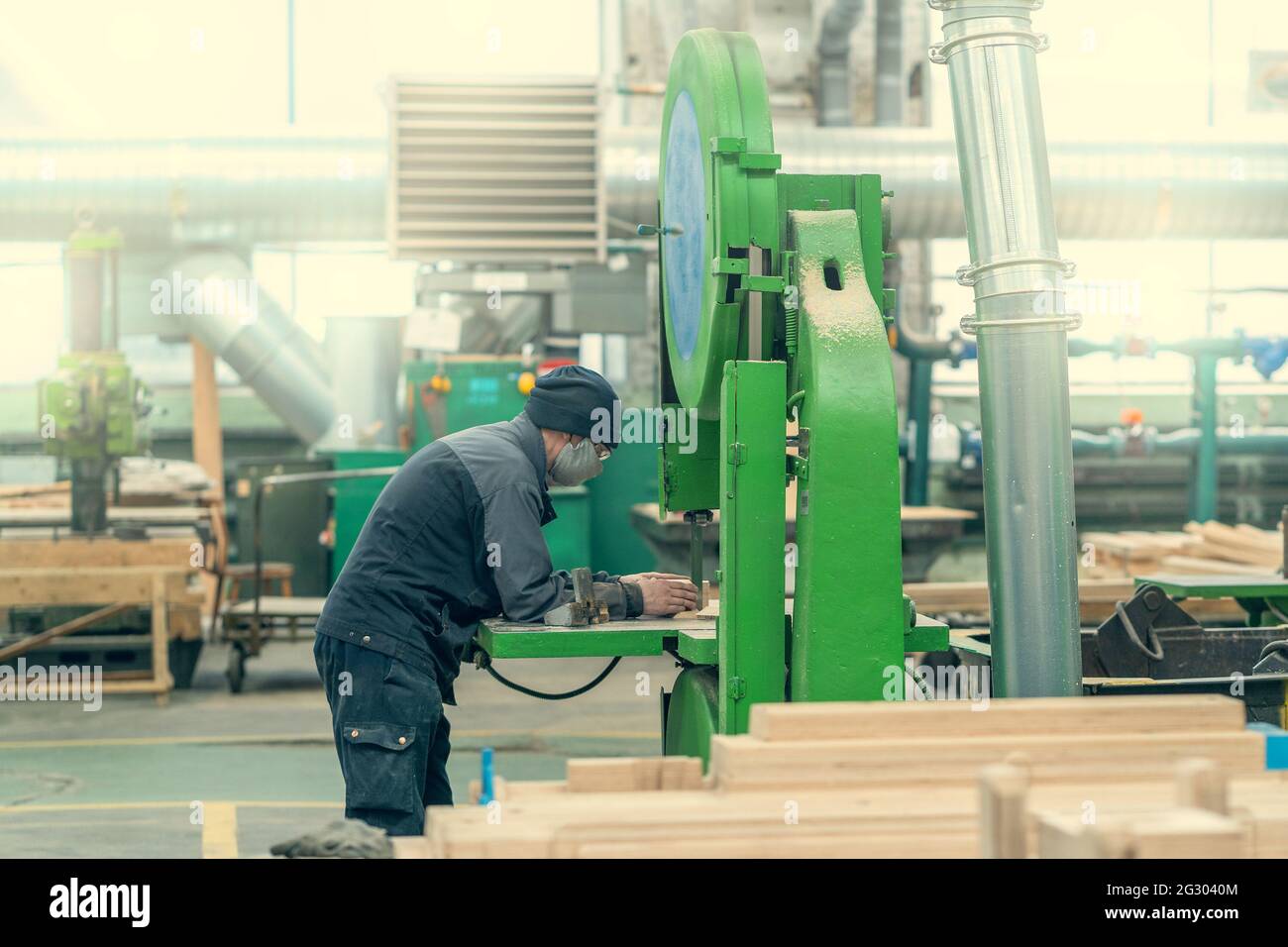 Worker at grinding machine for processing wood in workshop of ...