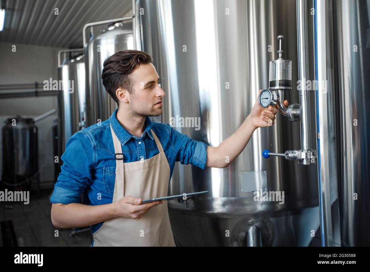 Brewery worker checking fermentation process in steel vat and look at ...