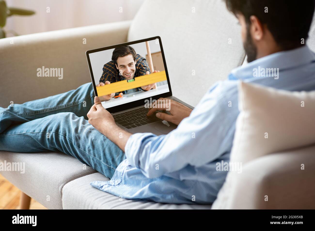 Young guy watching DIY video tutorial on laptop, learning how to fix or ...