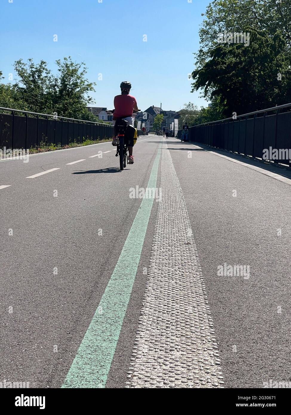 A woman riding a bicycle down the side of a road Stock Photo - Alamy