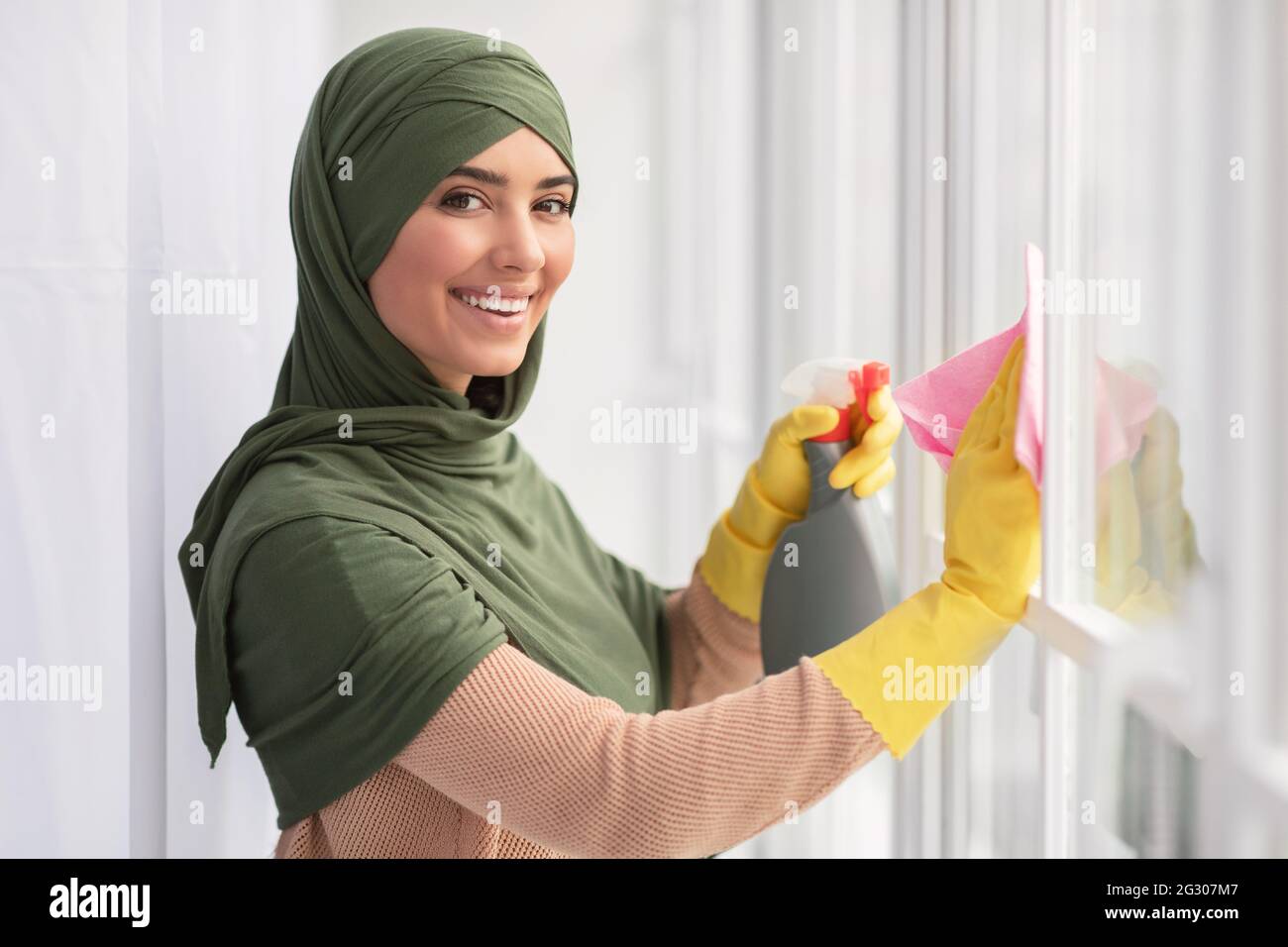 Muslim woman cleaning window with rag and cleanser spray Stock Photo ...