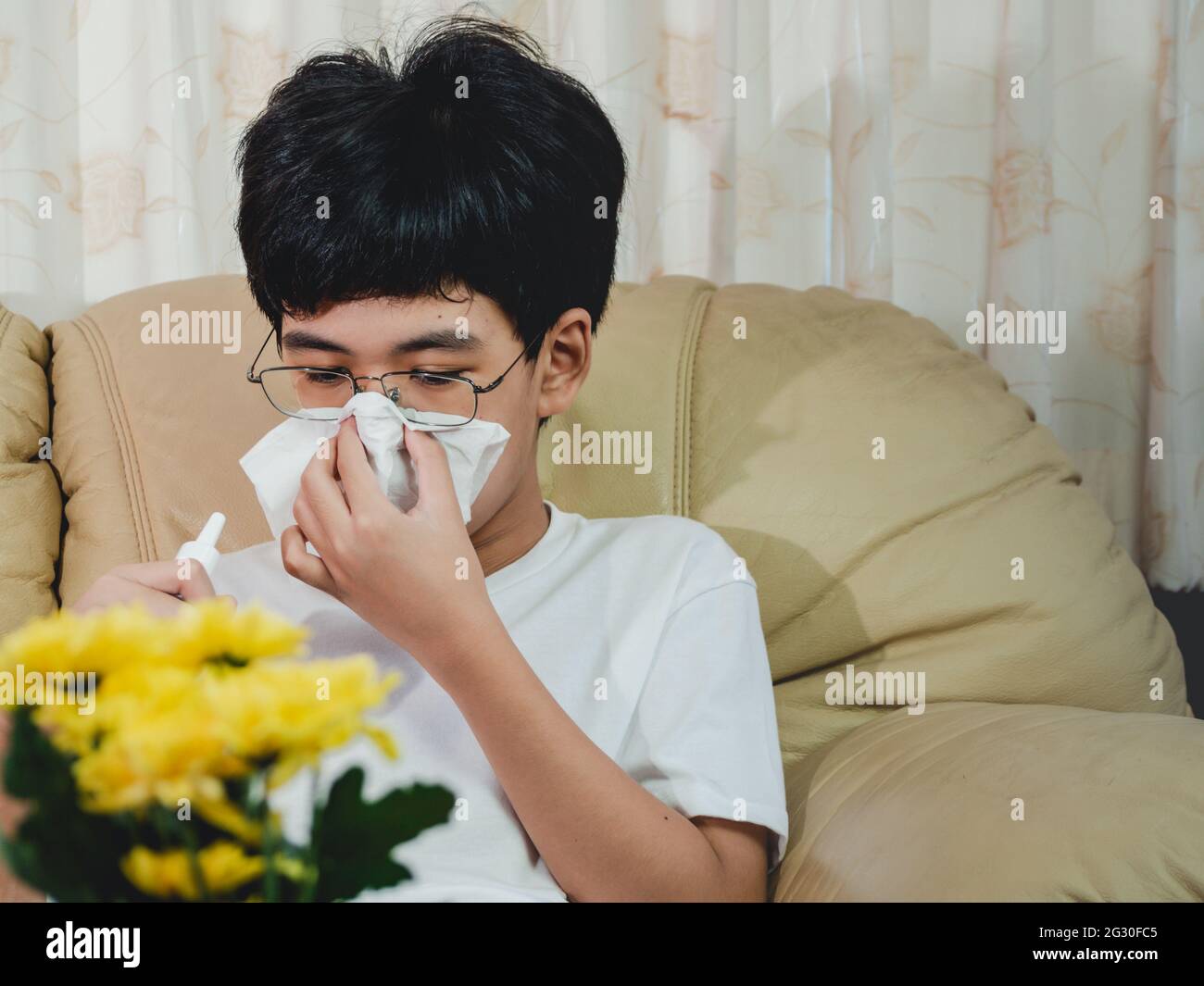 Young boy sneezing and blowing nose with nazal sprays because pollen ...