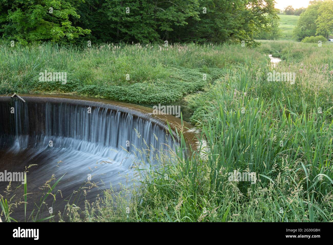 Long exposure of water cascading over a spillway along a creek Stock ...