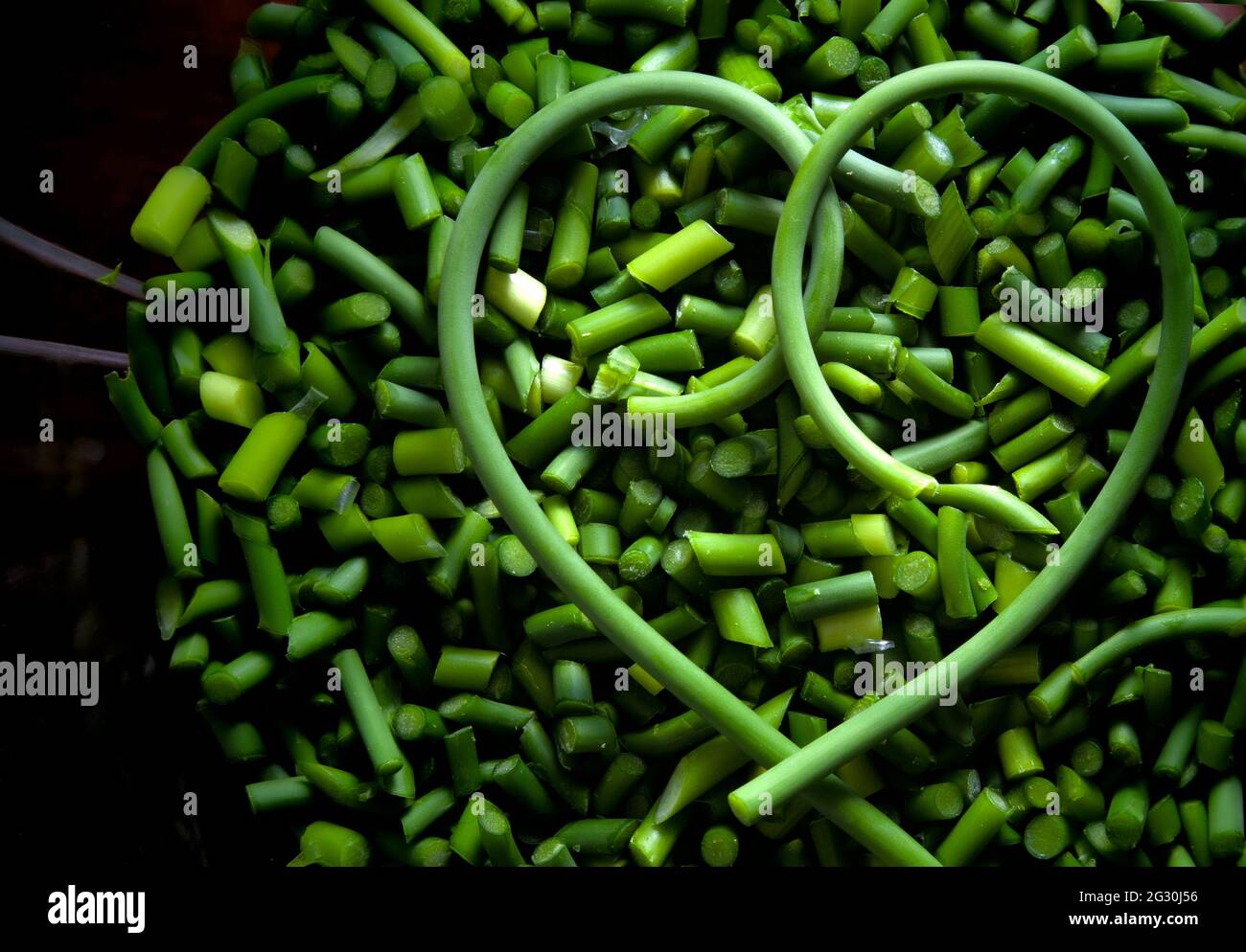Green garlic arrows in a heart-shaped plate Stock Photo - Alamy