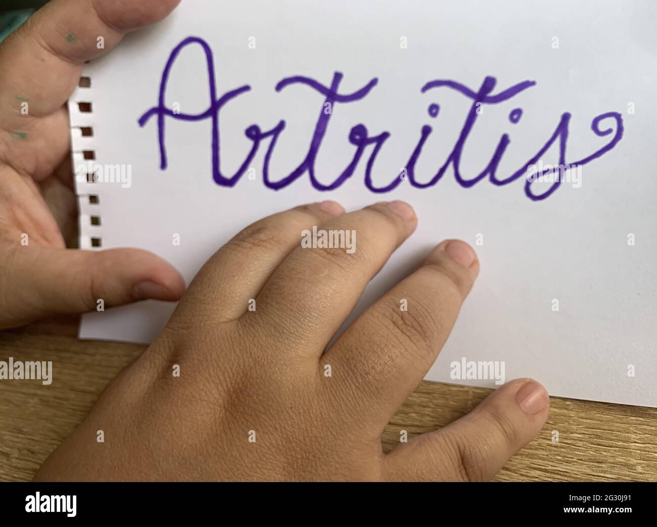 A high angle shot of male hands and a sheet of paper with "Arthritis ...