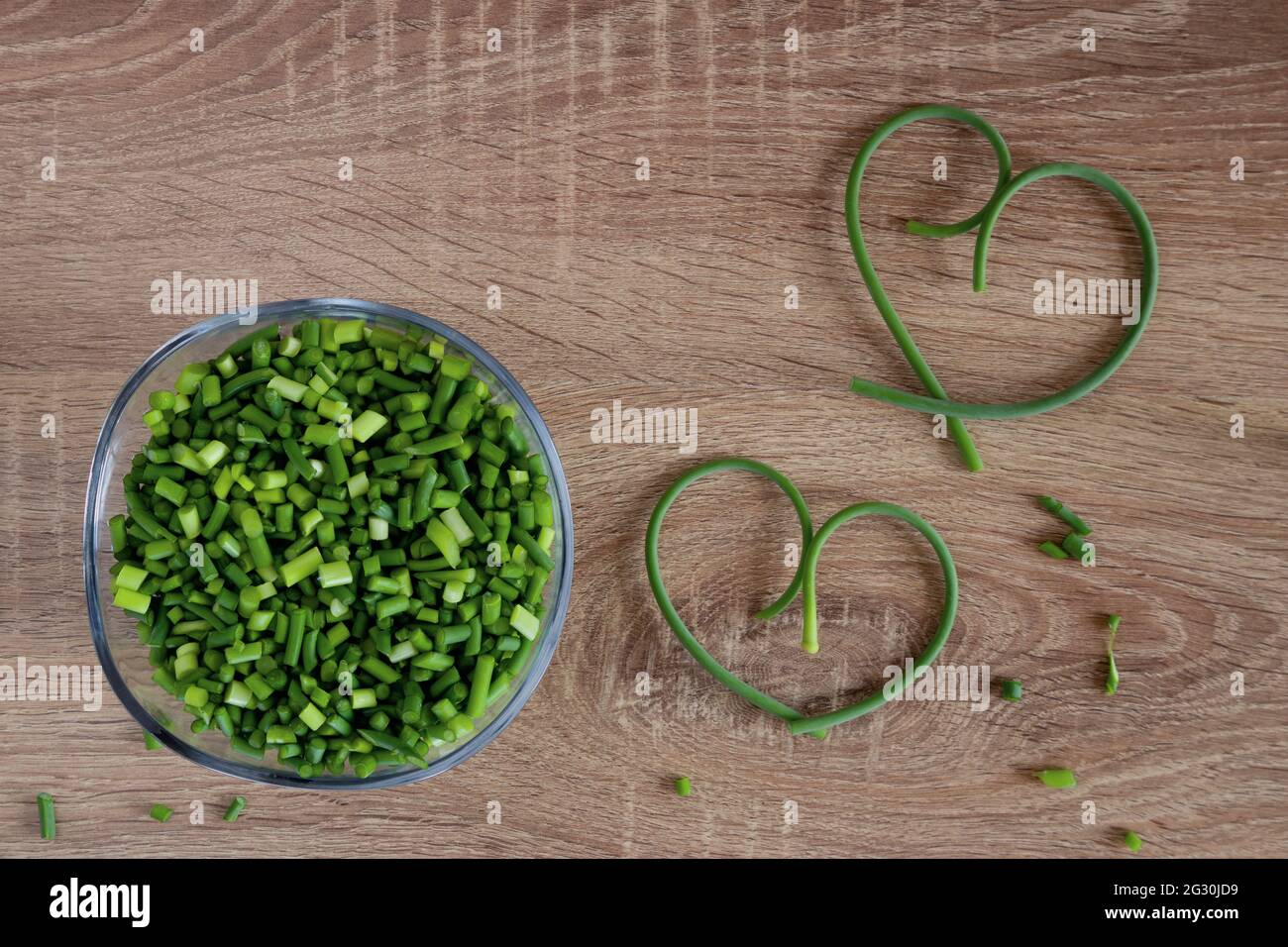 Heart shaped green garlic arrows on wooden background Stock Photo - Alamy