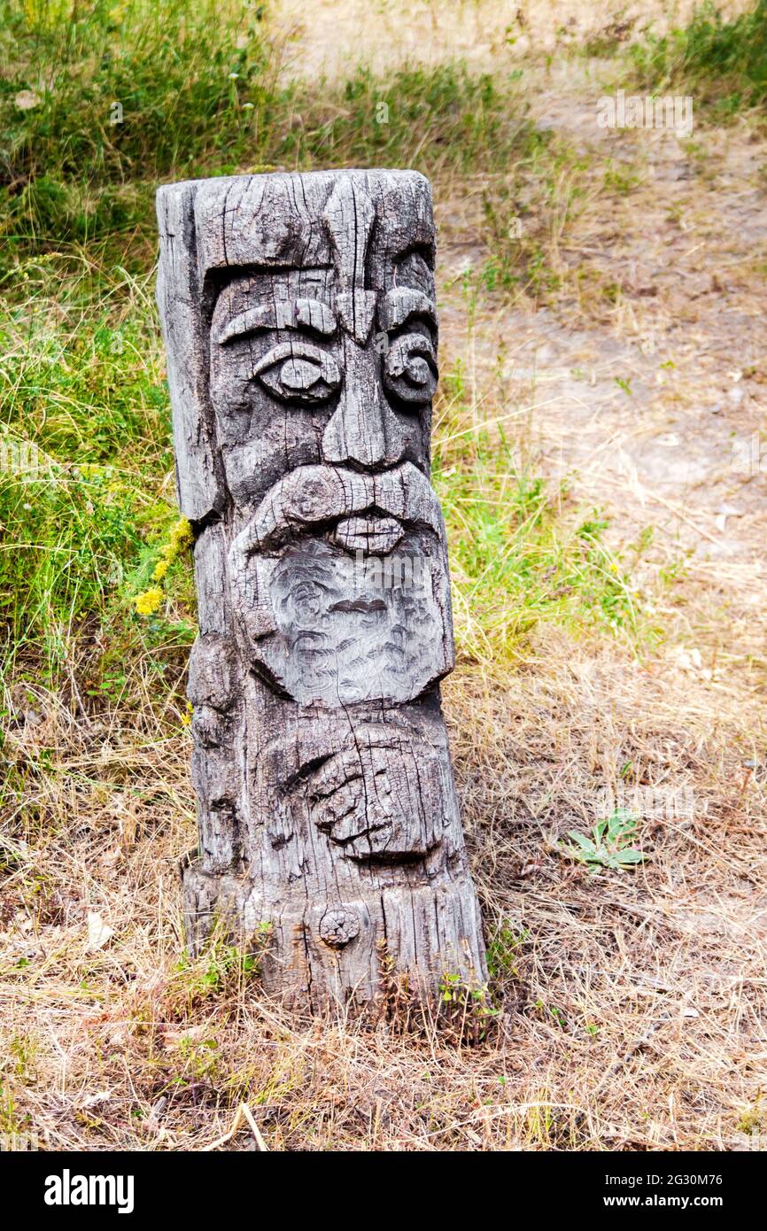 Wooden idol of Slavic god by a path in the forest. Forest in the ...
