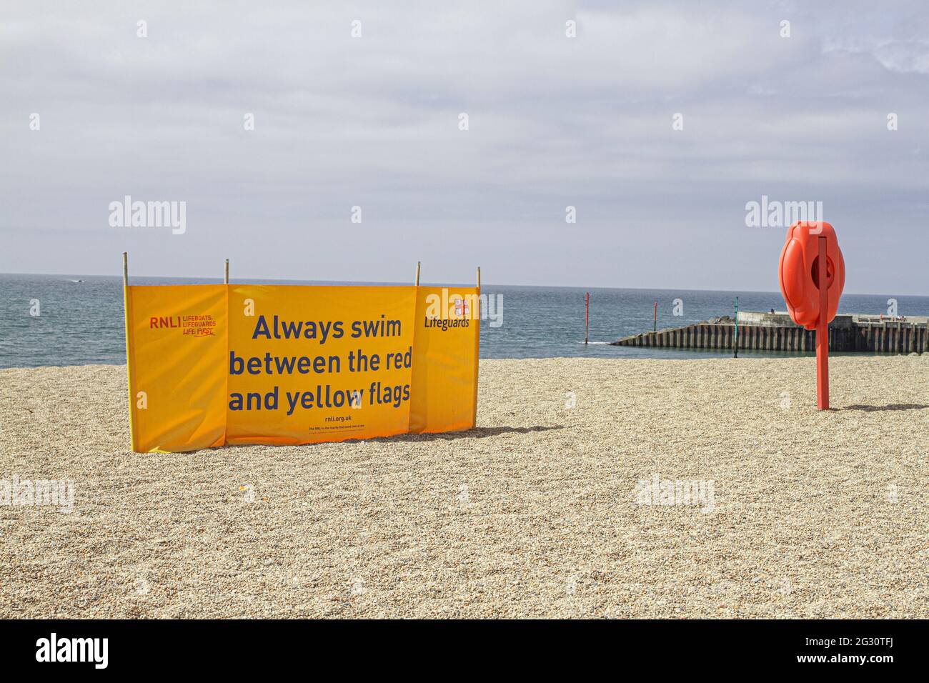 RNLI warning sign on the beach at West Bay, Jurassic Coast, Dorset ...