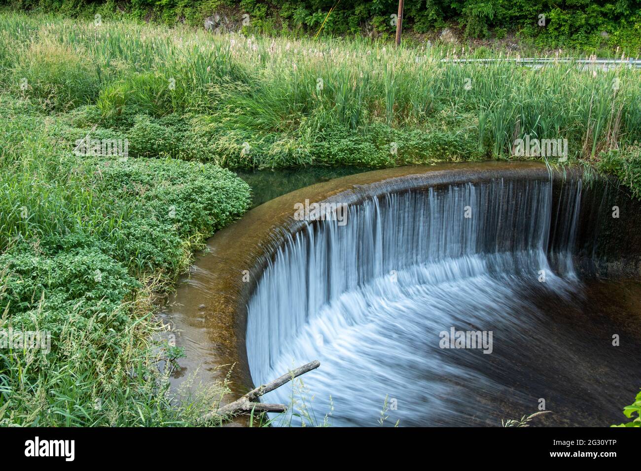 Long exposure of water cascading over a spillway along a creek Stock ...